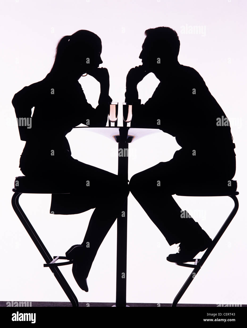Female and Male sitting at a high table on stools, resting and elbow in ...