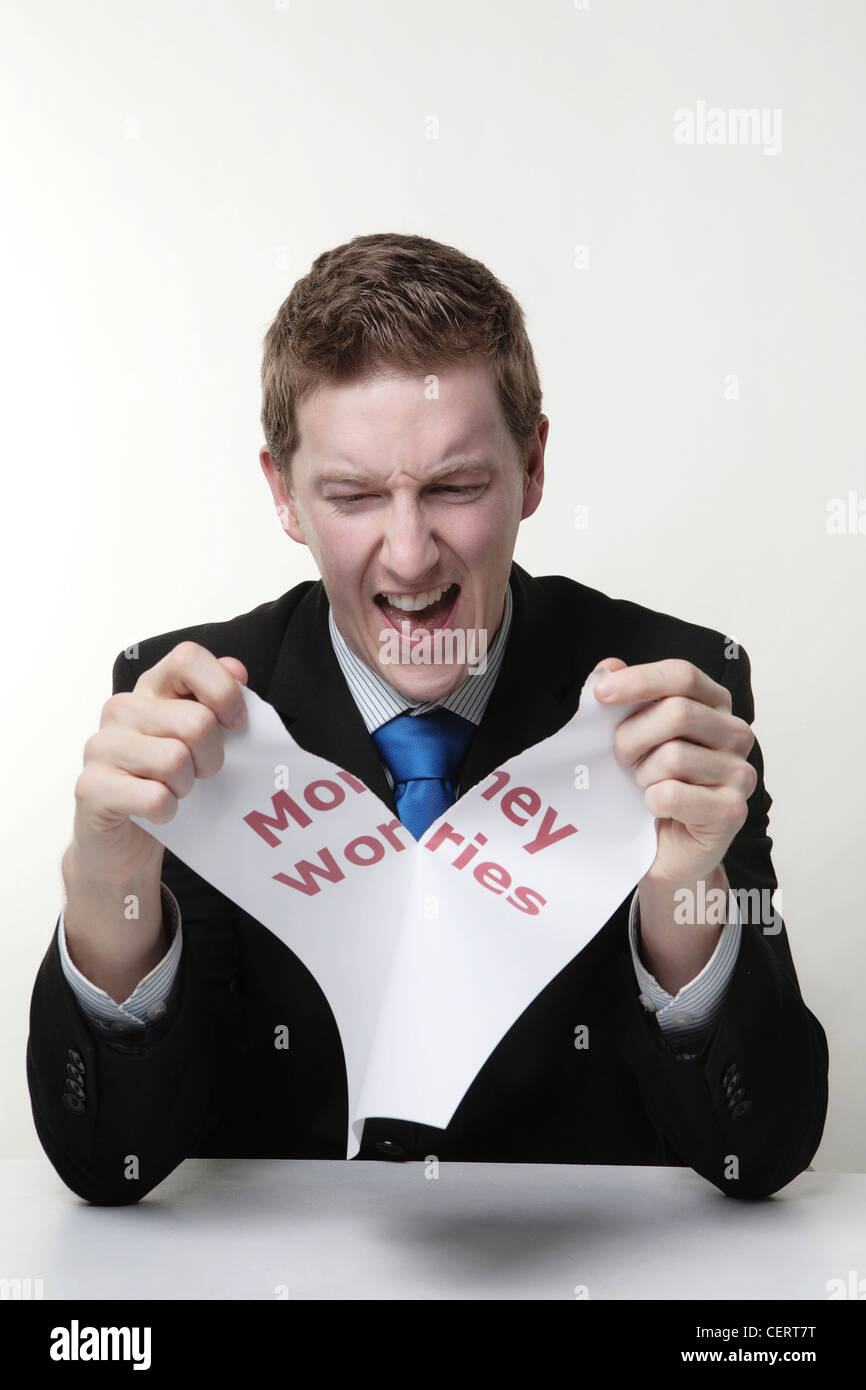 man in a suit sat at a desk ripping a piece of paper up with the words ...