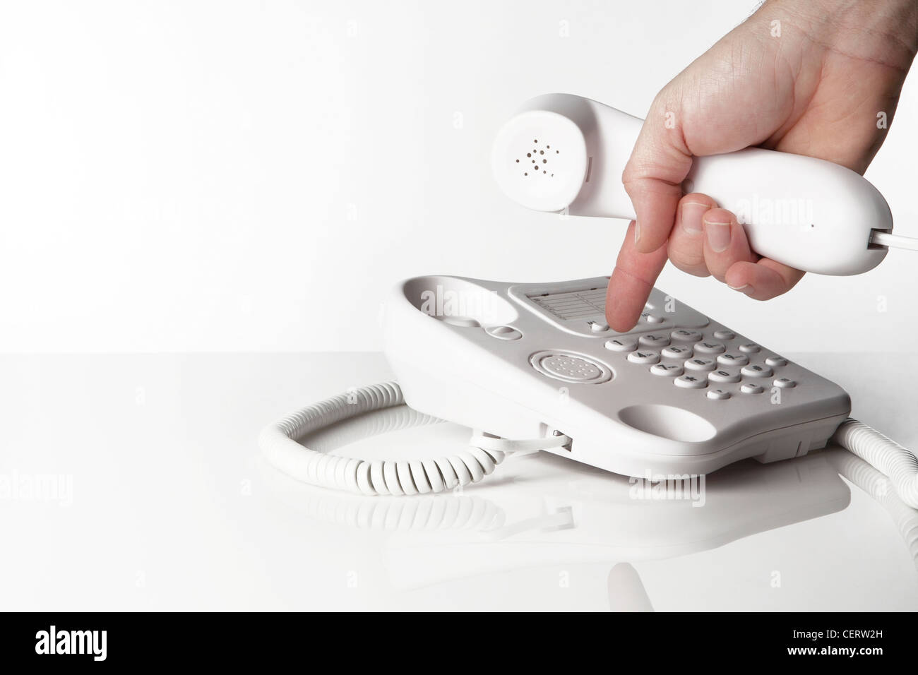 image of a telephone on a white background with a hand in the shot ...