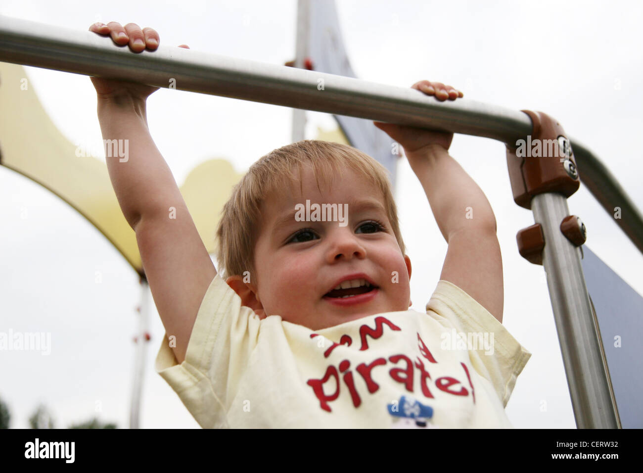 Male child in a park hanging from a railing Stock Photo - Alamy