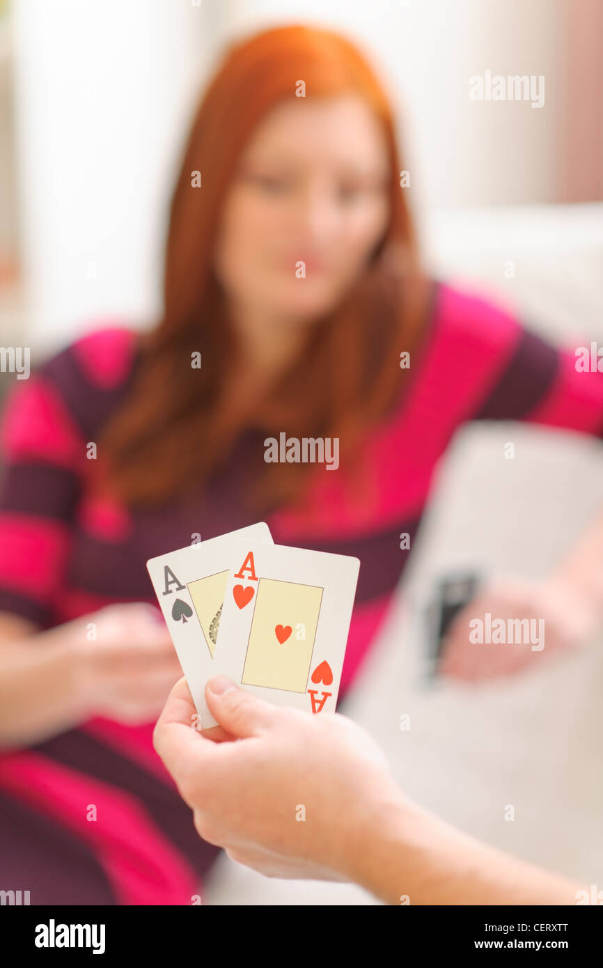 Closeup on hands with playing cards and woman in background Stock Photo ...