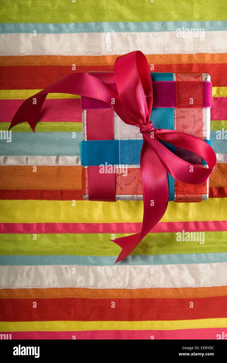 A still life of a present wrapped with woven satin ribbons, topped with ...