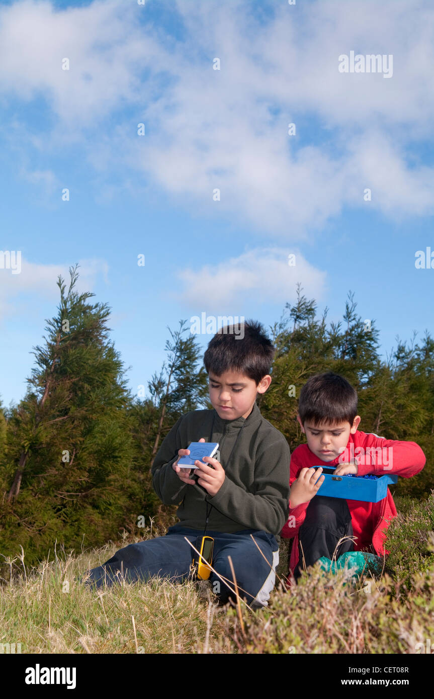 Two boys finding a geocache treasure in the hoods Stock Photo - Alamy