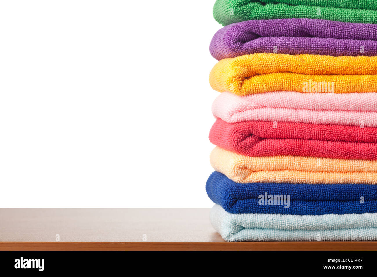 Stack of colorful microfiber towels on a table against white background ...