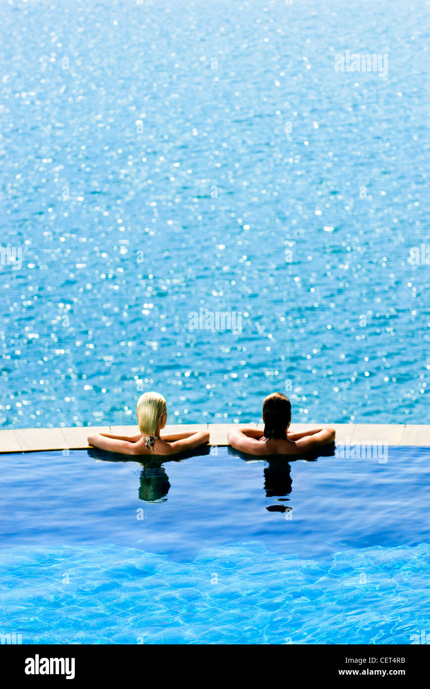 A young couple enjoys a romantic swim together at a tropical resort ...