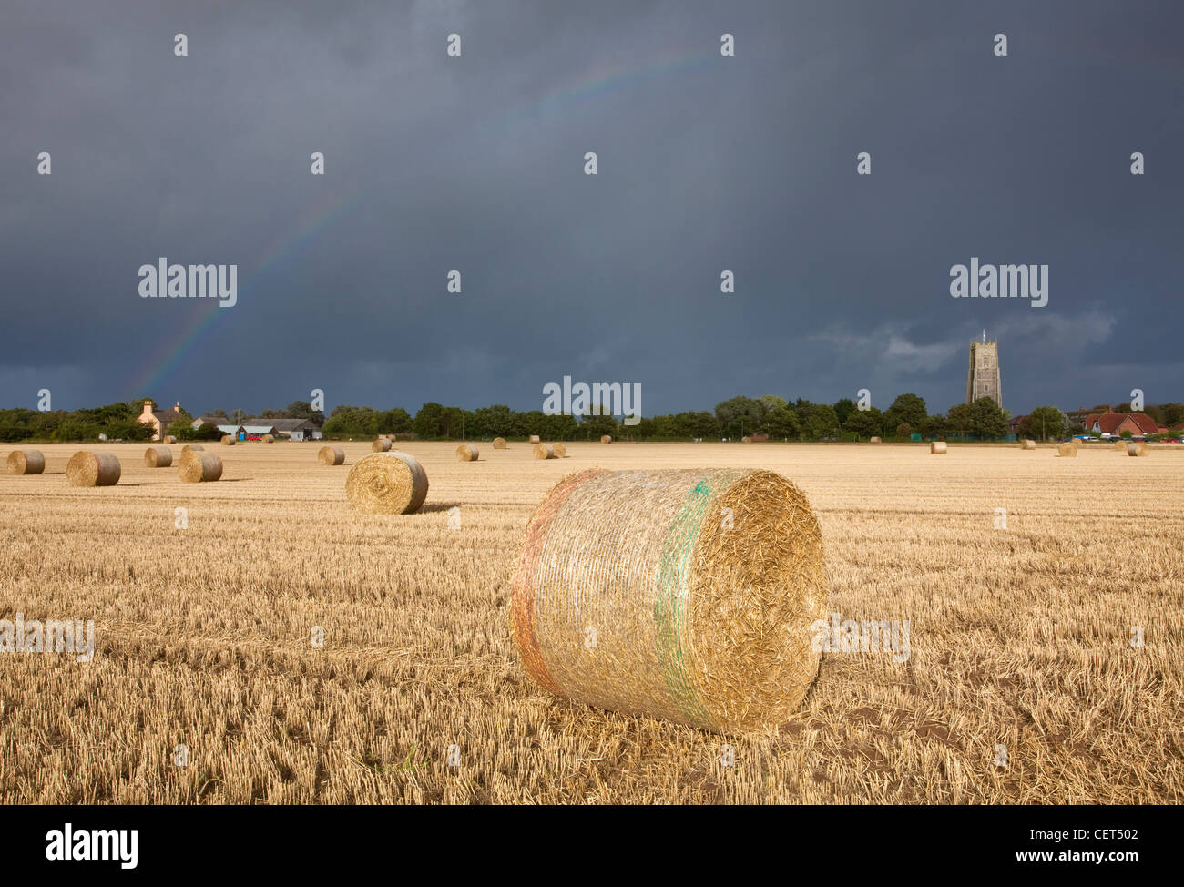 View over bales of hay towards a rainbow over Holy Trinity and All ...