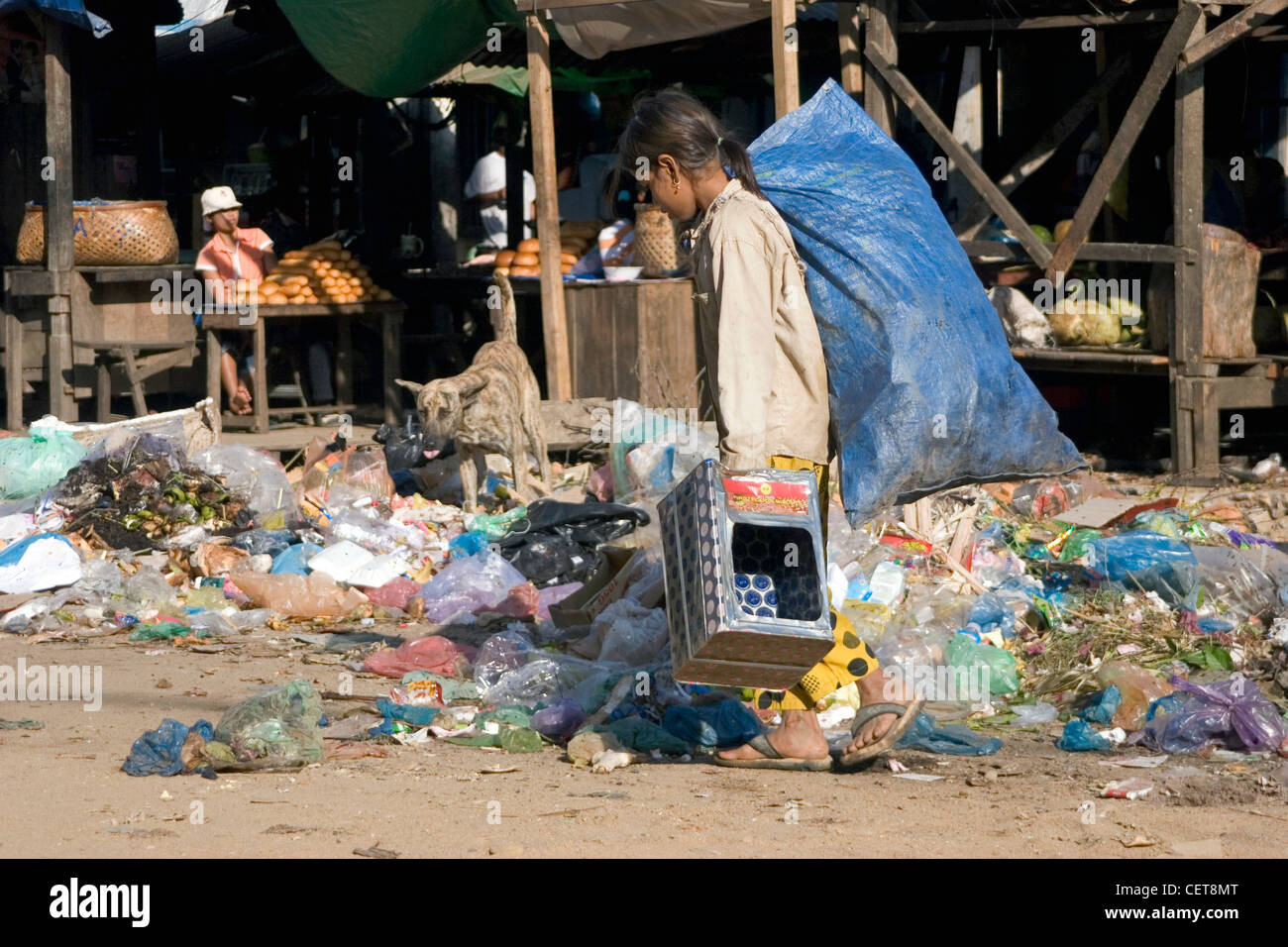 A young girl living in poverty is scavenging through garbage on a city ...
