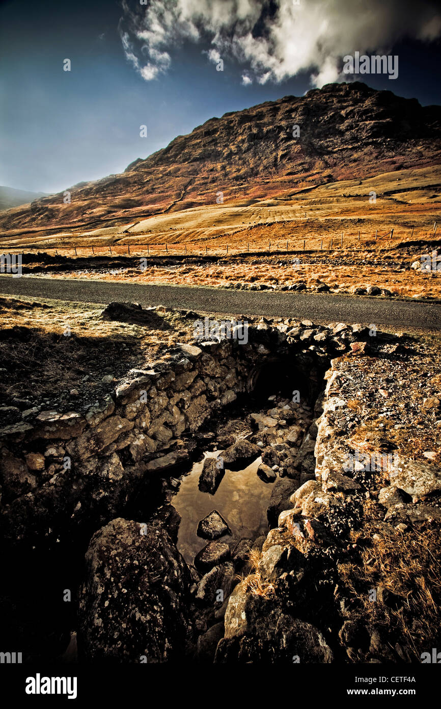 Rocky outcrops and mountains beside a road in the The Lake District ...