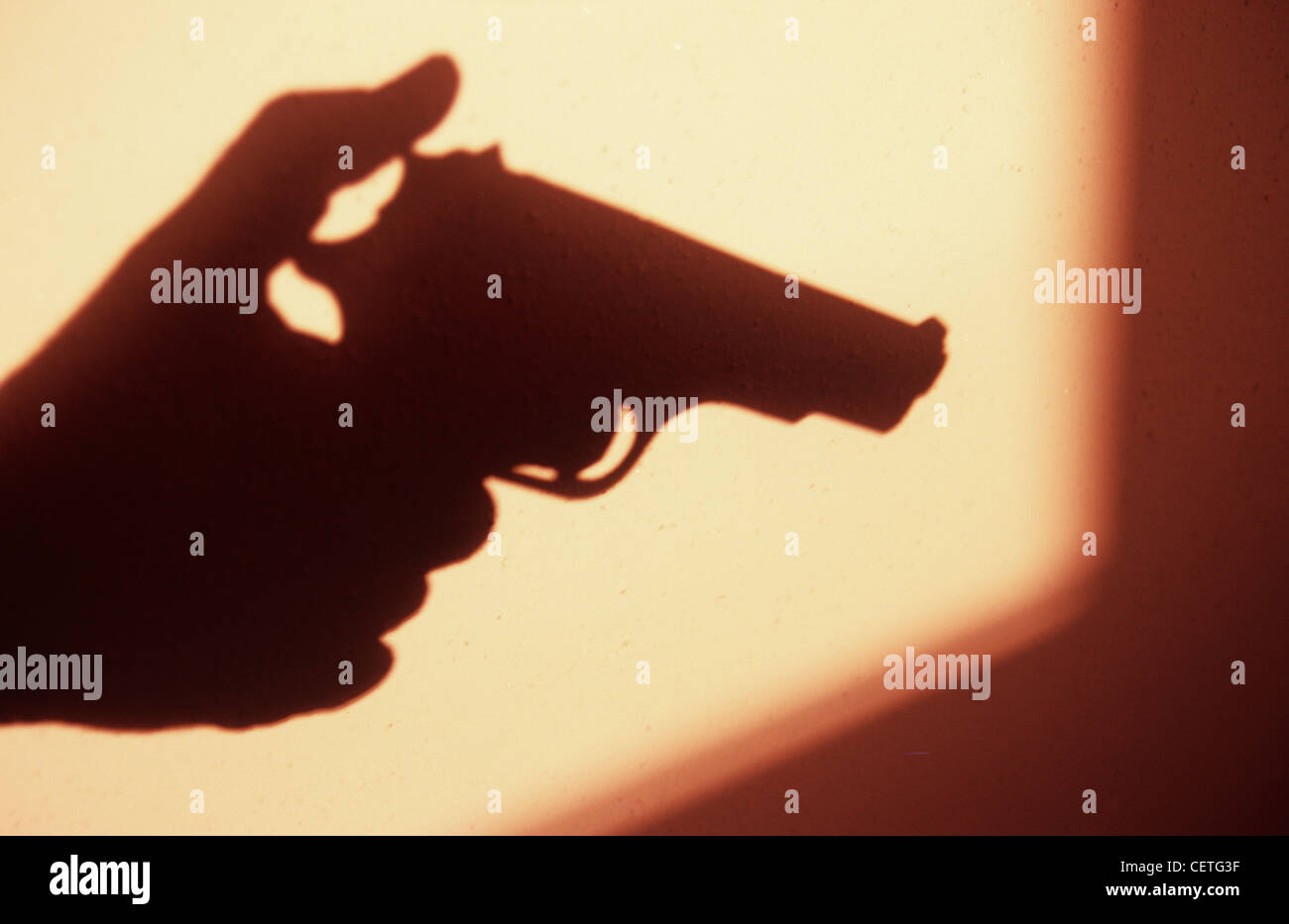 Shadow in warm light of window or door with hand holding gun and ...