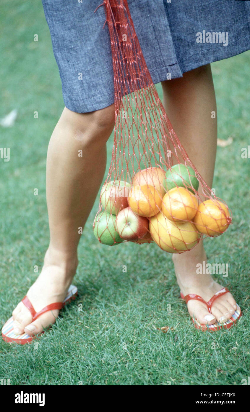 Cropped female legs wearing blue denim skirt and red flip flops ...