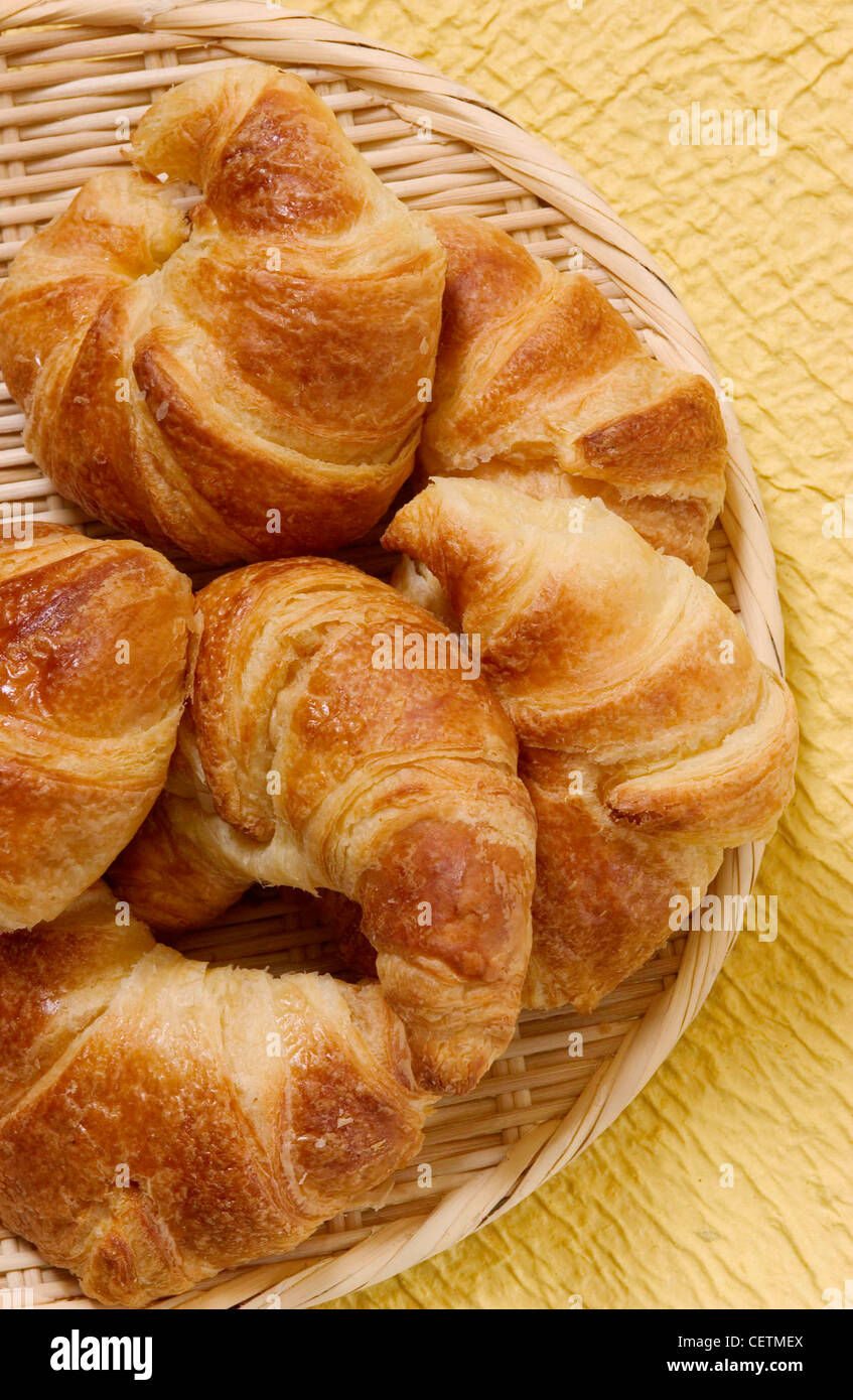 Aerial view of basket of plain croissants on yellow table Stock Photo ...