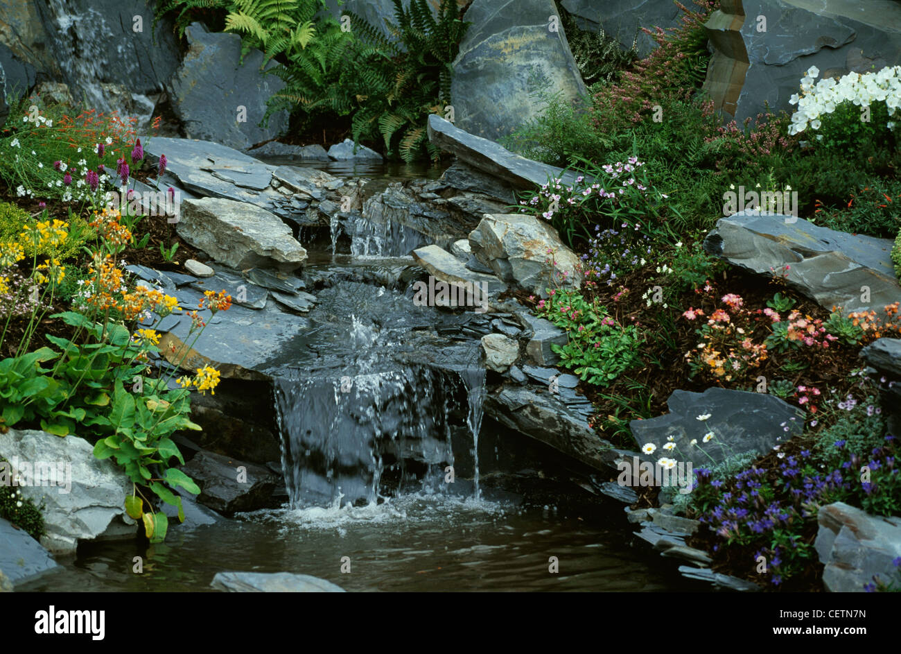 Three small waterfalls cascade down a water feature set in stone ...