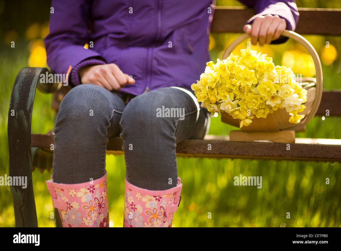 woman sitting on a bench with a trug of daffodils Stock Photo - Alamy