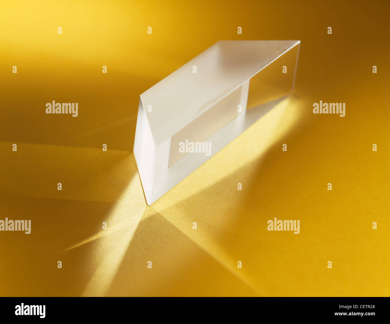 A glass prism with reflections of light on a bright yellow background ...