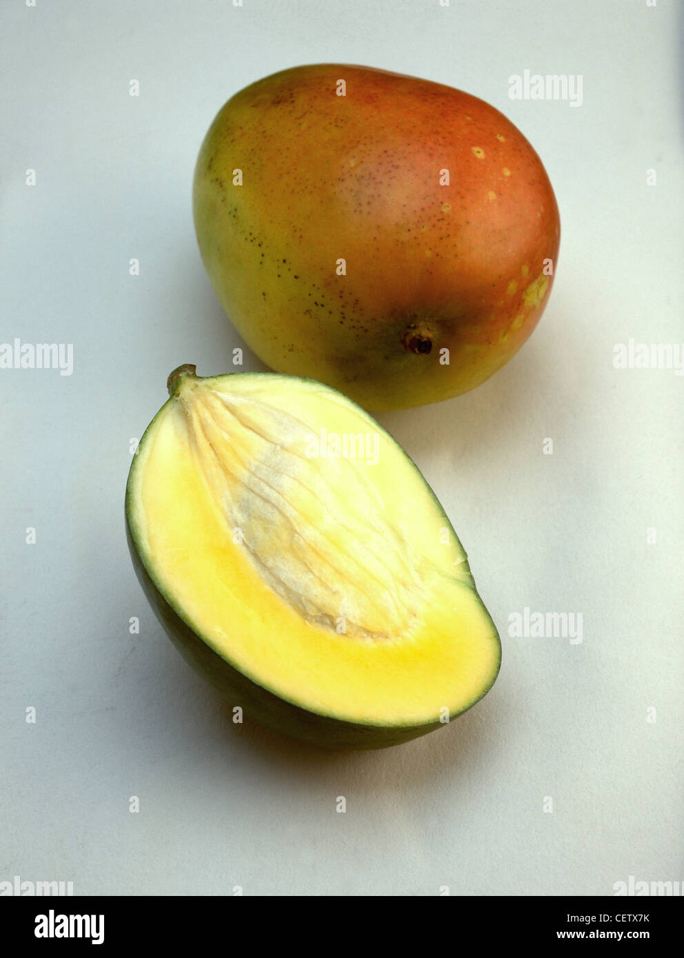 Whole mango and mango sliced in half against white background Stock ...