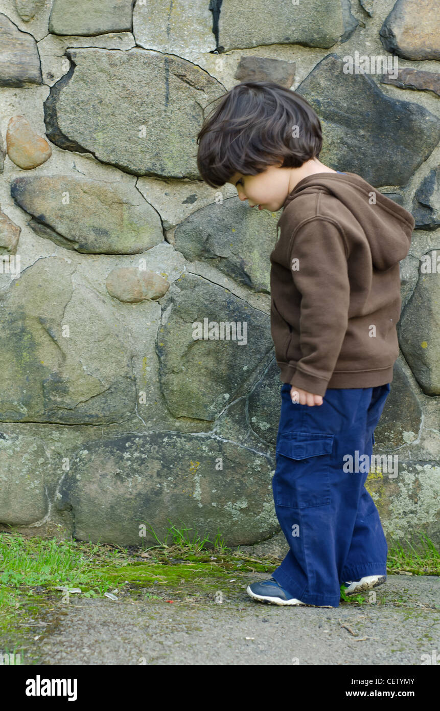 A boy walking while looking down at the grass Stock Photo - Alamy