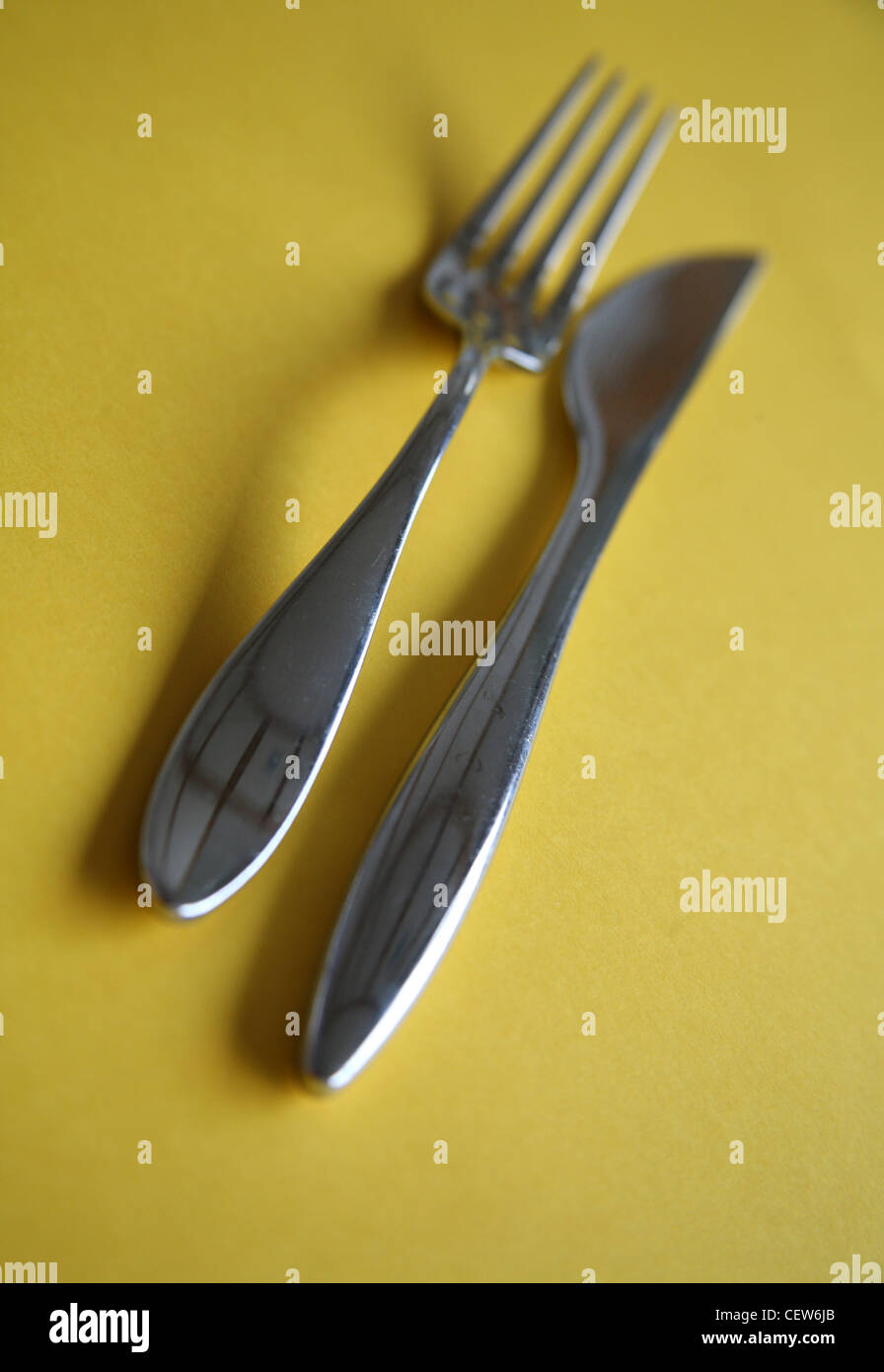 Knife and fork on colourful yellow background Stock Photo - Alamy