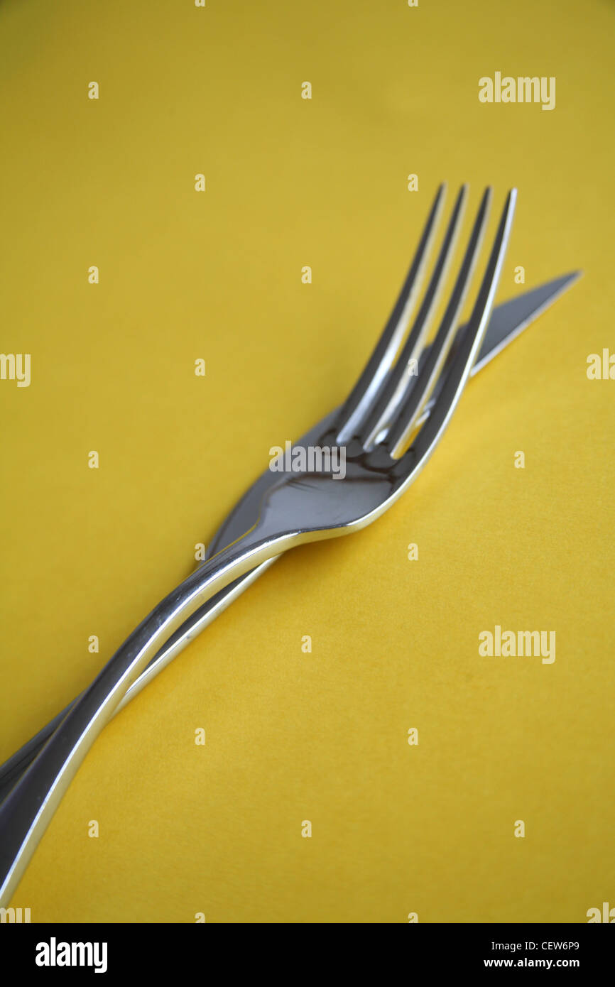 Knife and fork on colourful yellow background Stock Photo - Alamy
