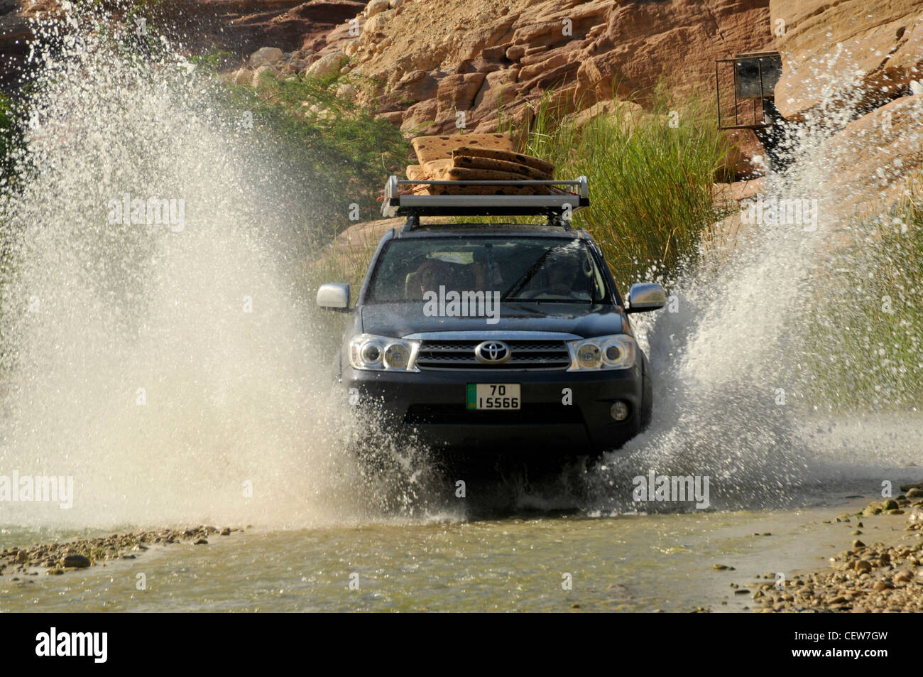 Head-on view of an suv 4x4 vehicle driving fast through water in a ...