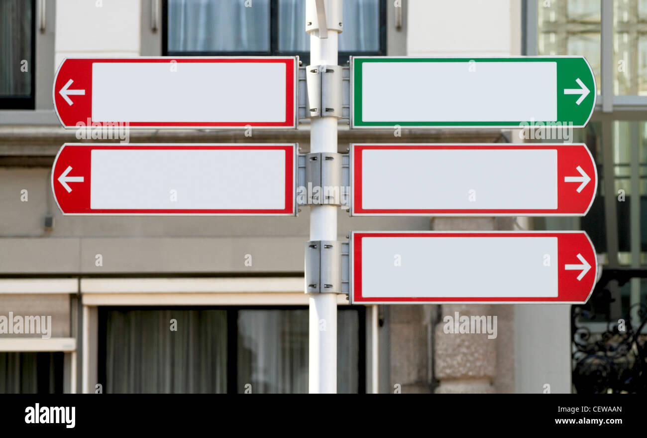 Four red and one green directional sign post, pointing to the left and ...