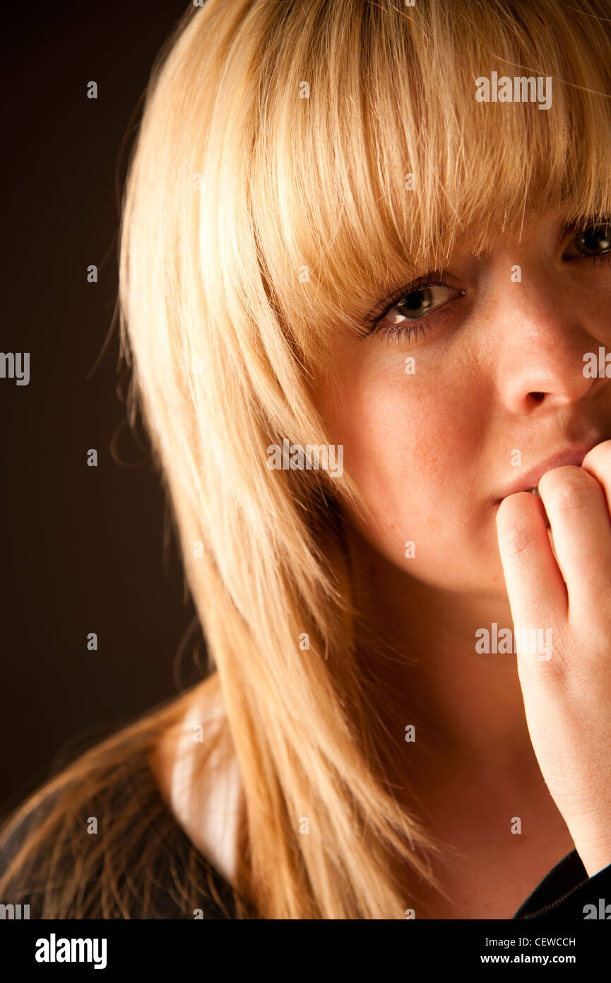 a sad tearful crying upset , blonde haired teenage girl woman biting ...