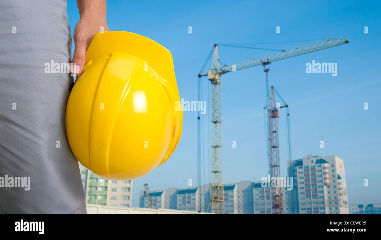 Closeup of builder with yellow helmet on building panorama background ...