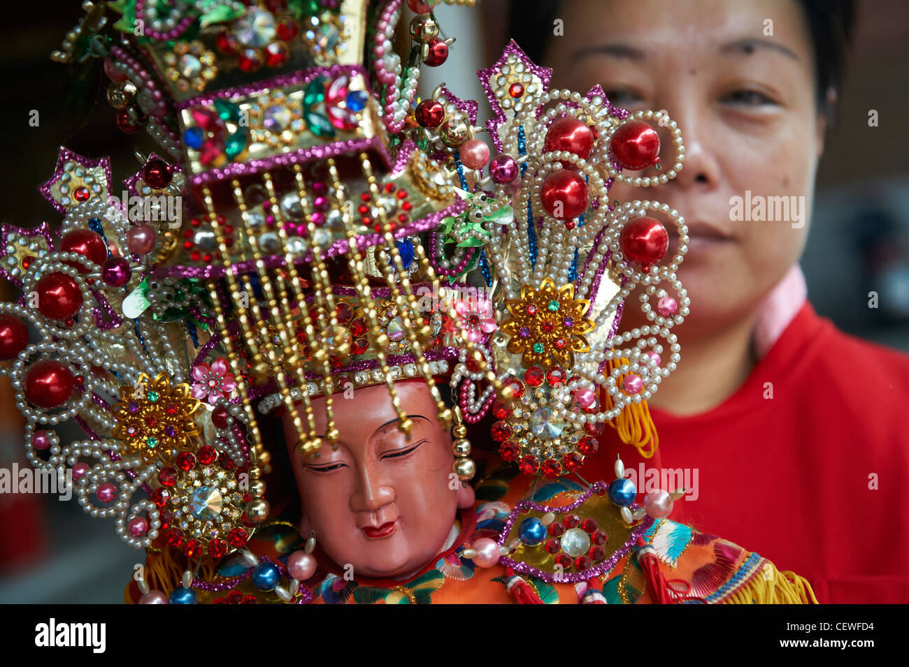 A woman holding a statue of a Daoist God in front of the Zushi Temple ...