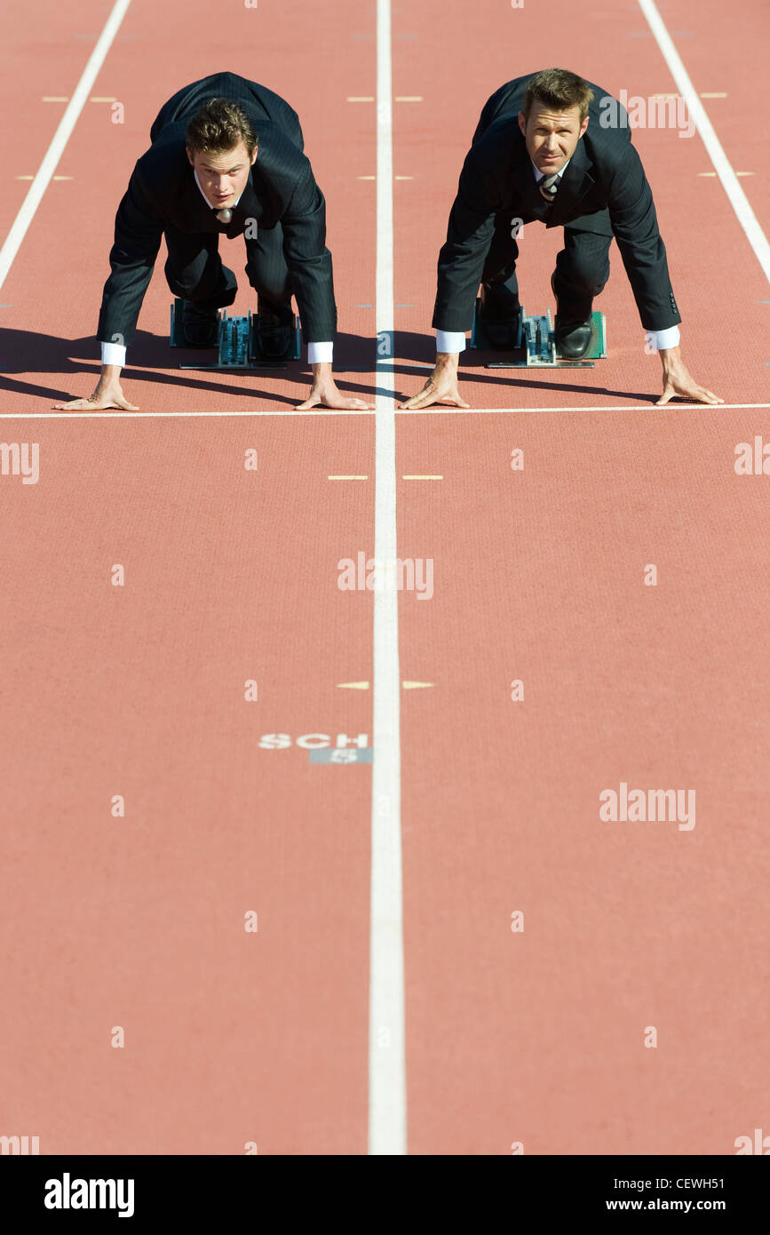 Businessmen crouched in starting position on running track Stock Photo ...