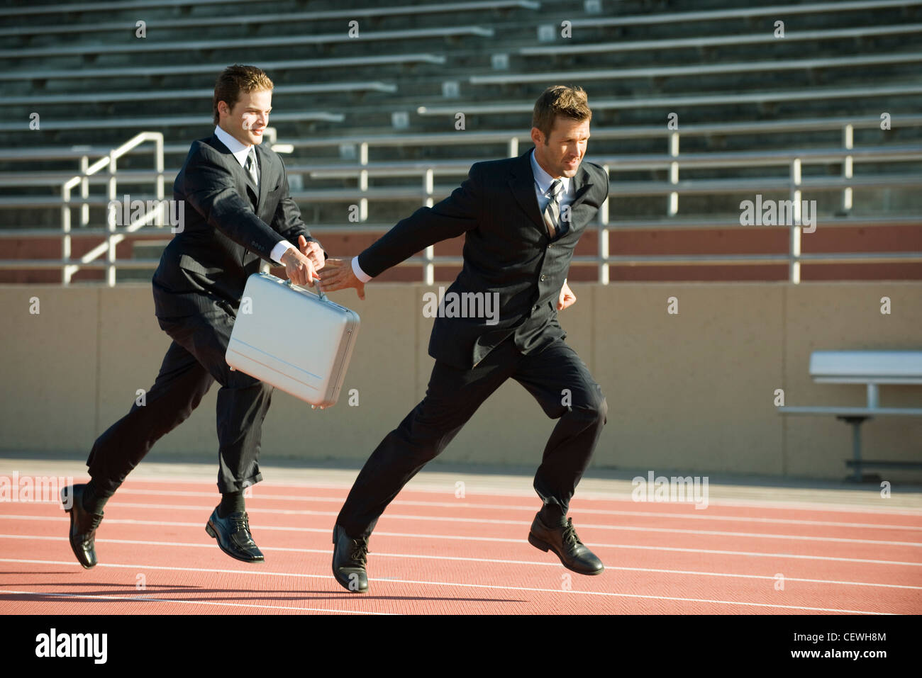 Businessmen running in relay race, handing off briefcase Stock Photo ...
