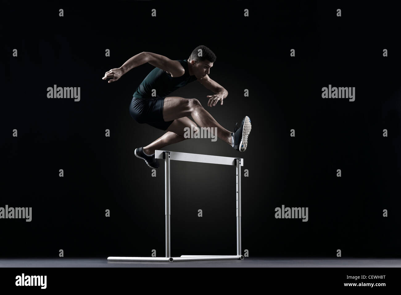 Male athlete clearing hurdle Stock Photo - Alamy