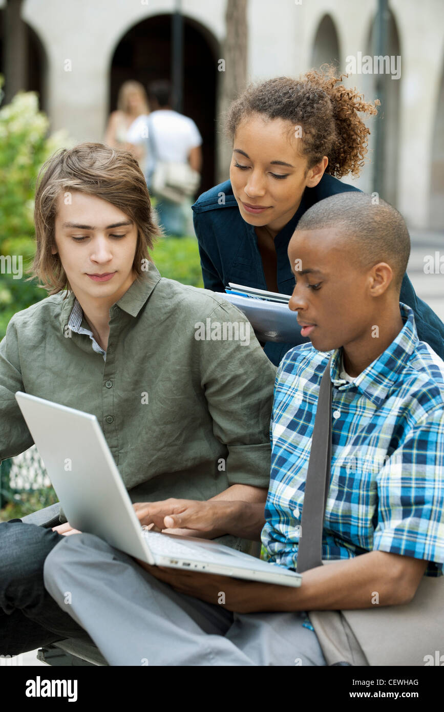 University students discussing homework on campus with laptop computer ...