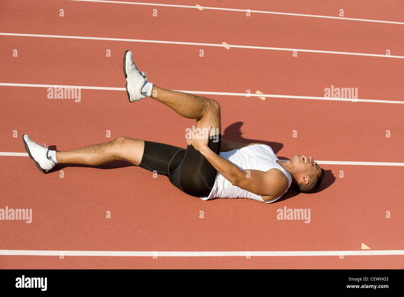 Injured runner lying on running track Stock Photo - Alamy