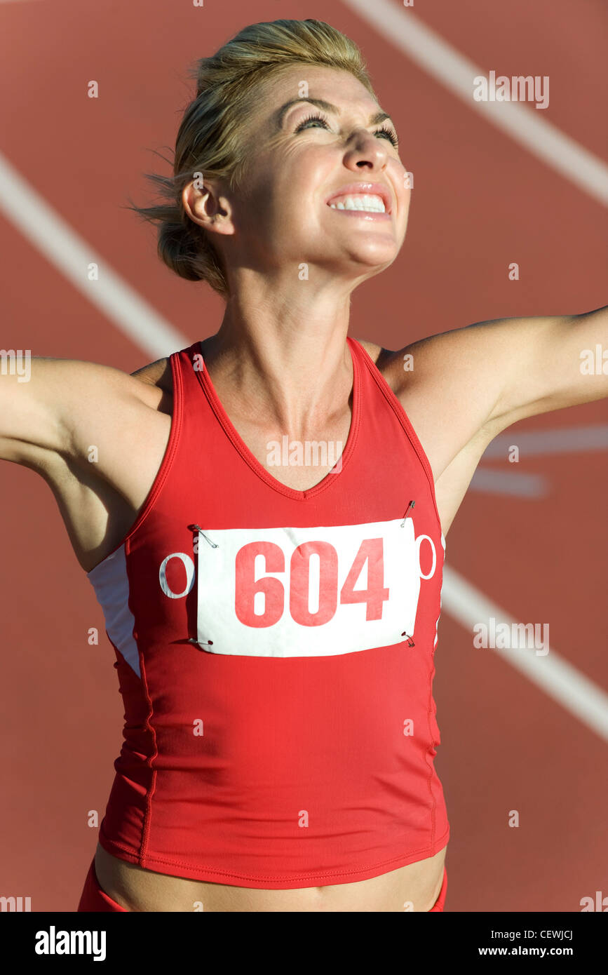 Woman running on track, looking up victoriously Stock Photo - Alamy