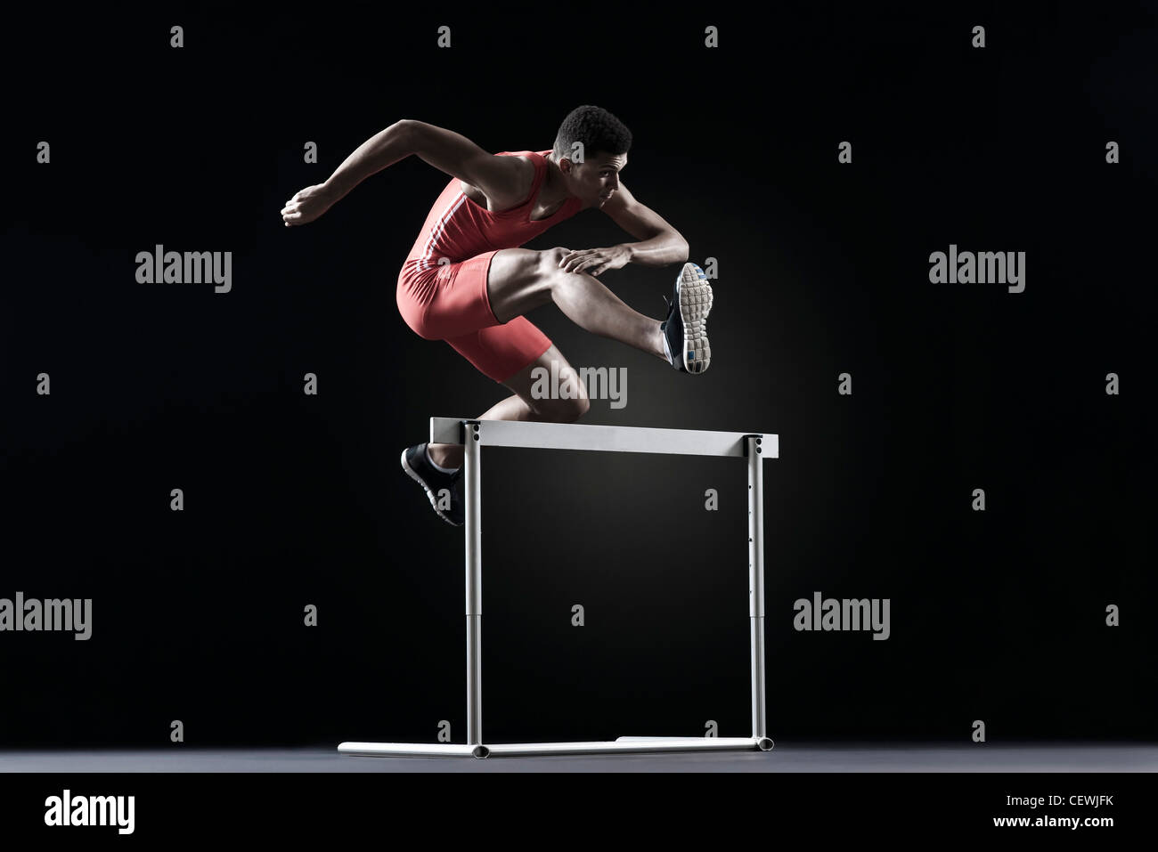 Male athlete clearing hurdle Stock Photo - Alamy