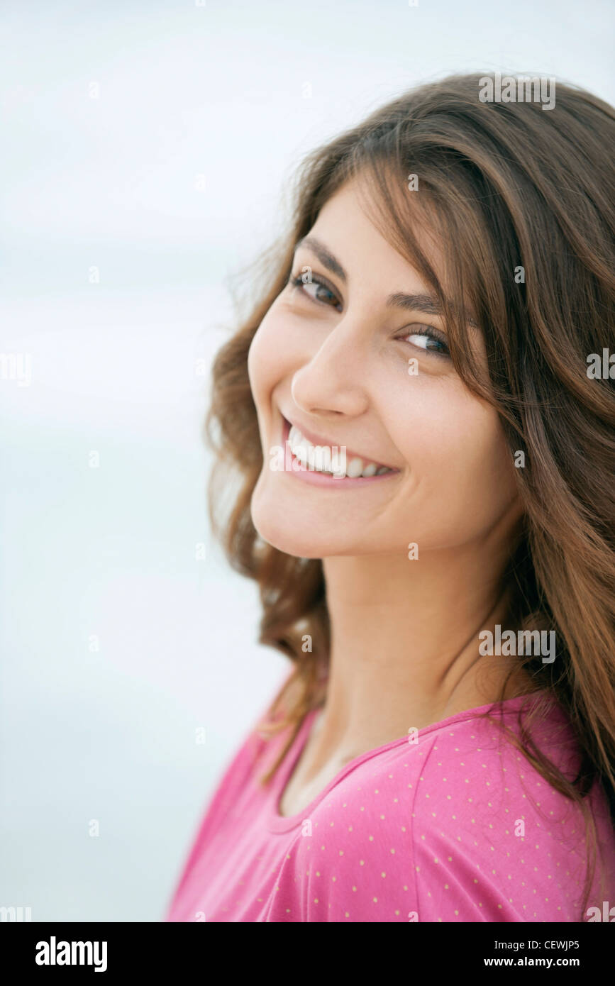 Young woman smiling over shoulder, portrait Stock Photo - Alamy