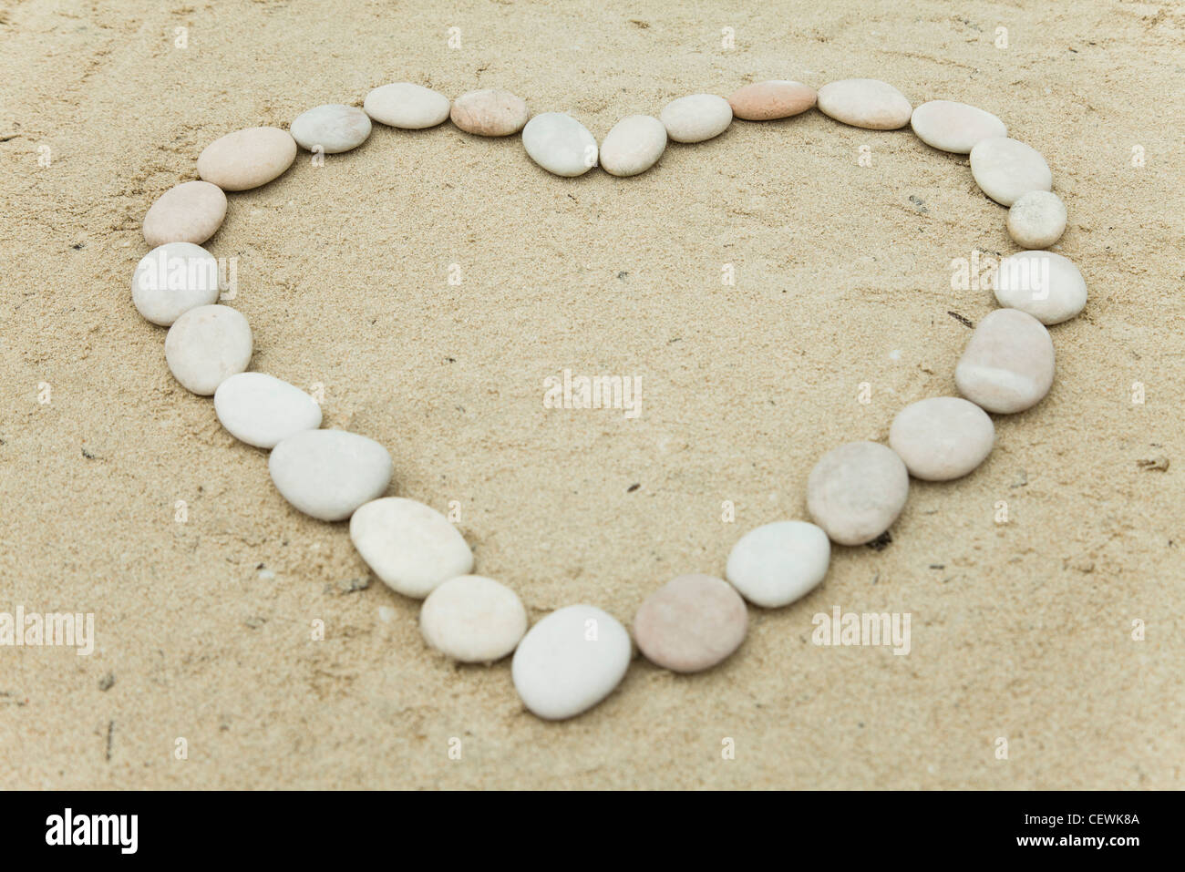 Pebbles arranged in heart shape on sand Stock Photo - Alamy