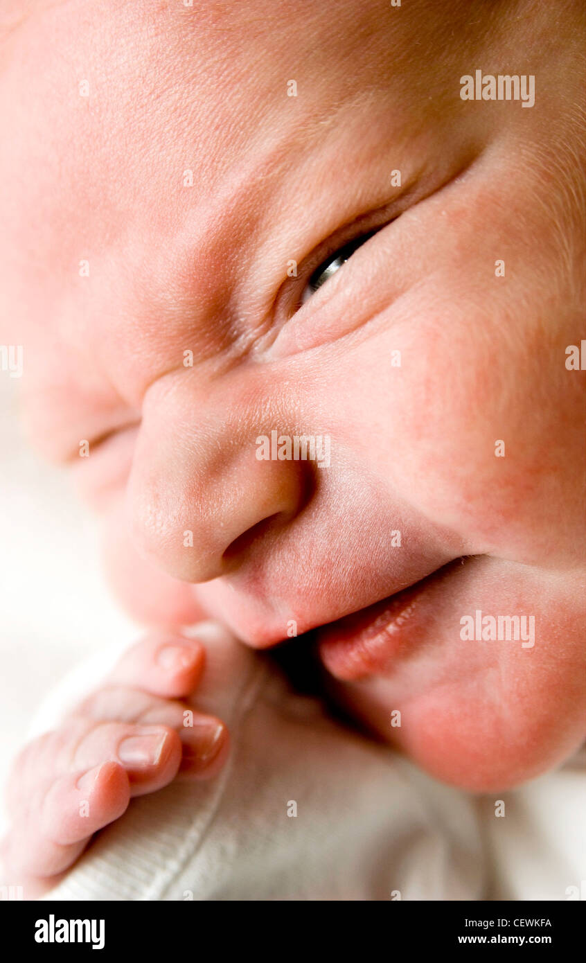 Close up of new born baby in half profile, looking sad with face ...