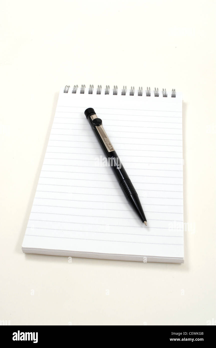 A spiral bound pad of paper with a black pen ball point pen placed on ...