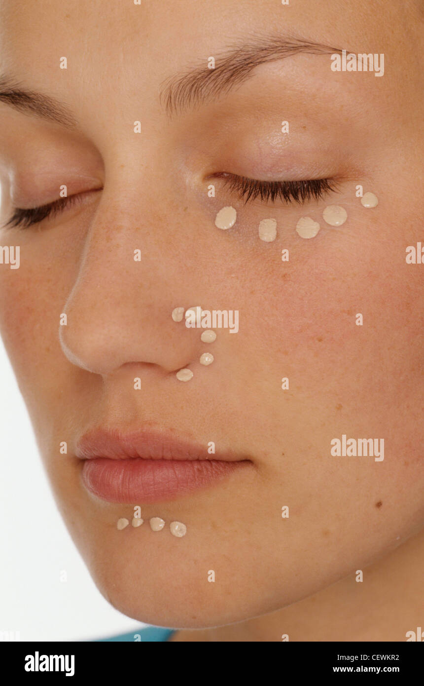 lose up of a female face eyes closed with foundation beads under one ...