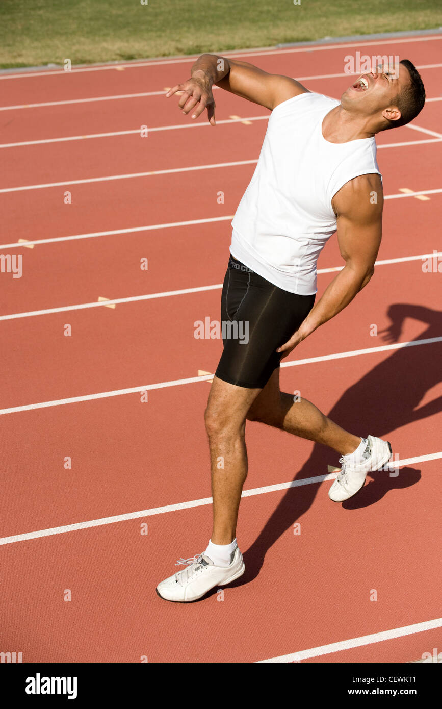 Runner on running track with painful expression Stock Photo - Alamy