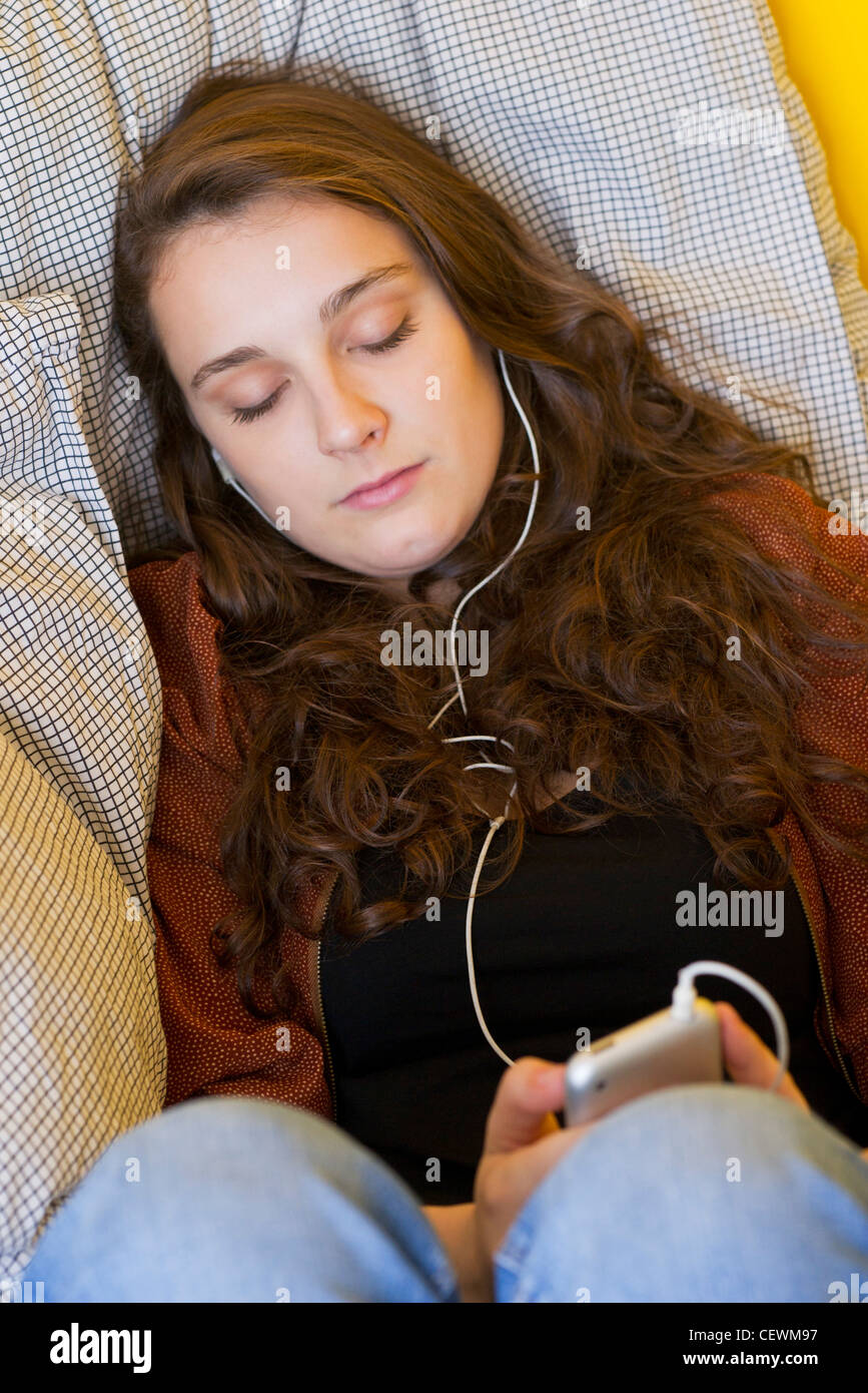 Young woman listening to MP3 player with eyes closed Stock Photo - Alamy