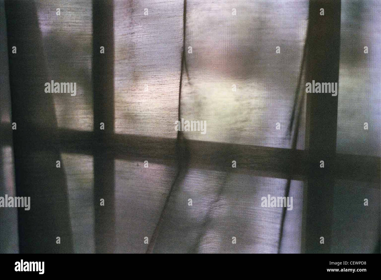 Window frame concealed by curtain fabric with light and colours showing ...