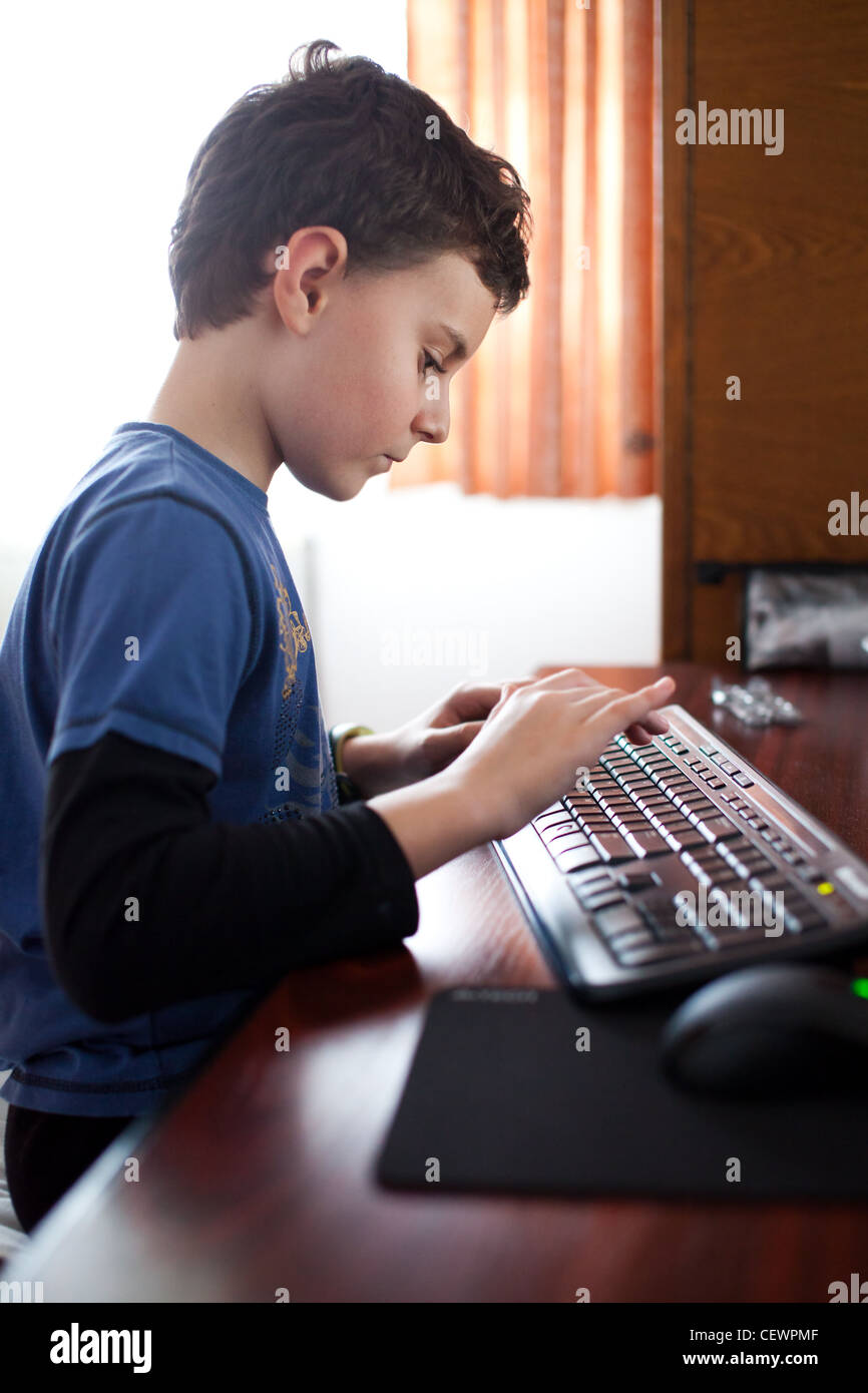 Indoor shot of a boy typing on a keyboard Stock Photo - Alamy