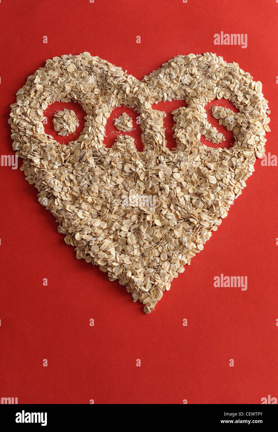 A still life image of dry porridge oats in heart shape on red ...