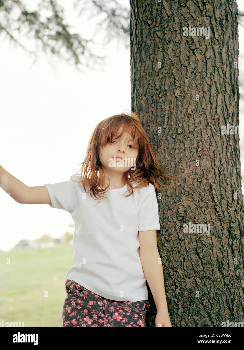 Female child standing leaning against tree Stock Photo - Alamy