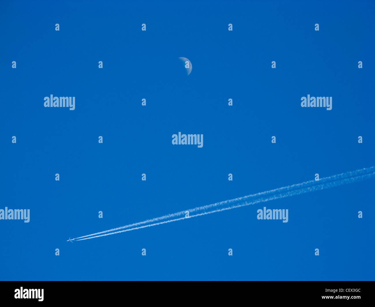 A contrail and the moon in the early evening Stock Photo - Alamy