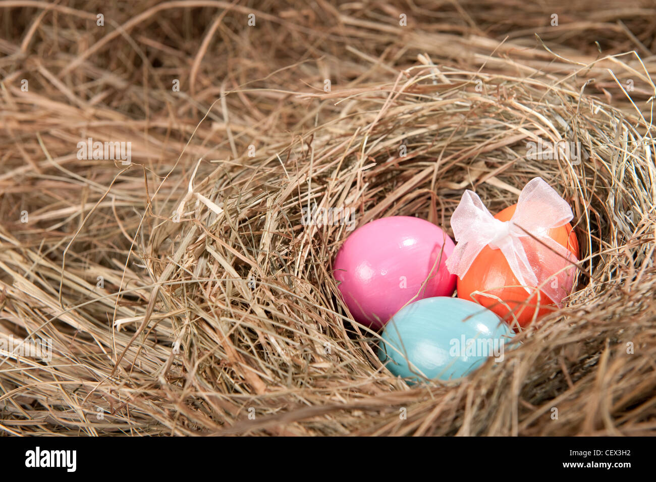 Three colorful Easter eggs in straw nest Stock Photo - Alamy
