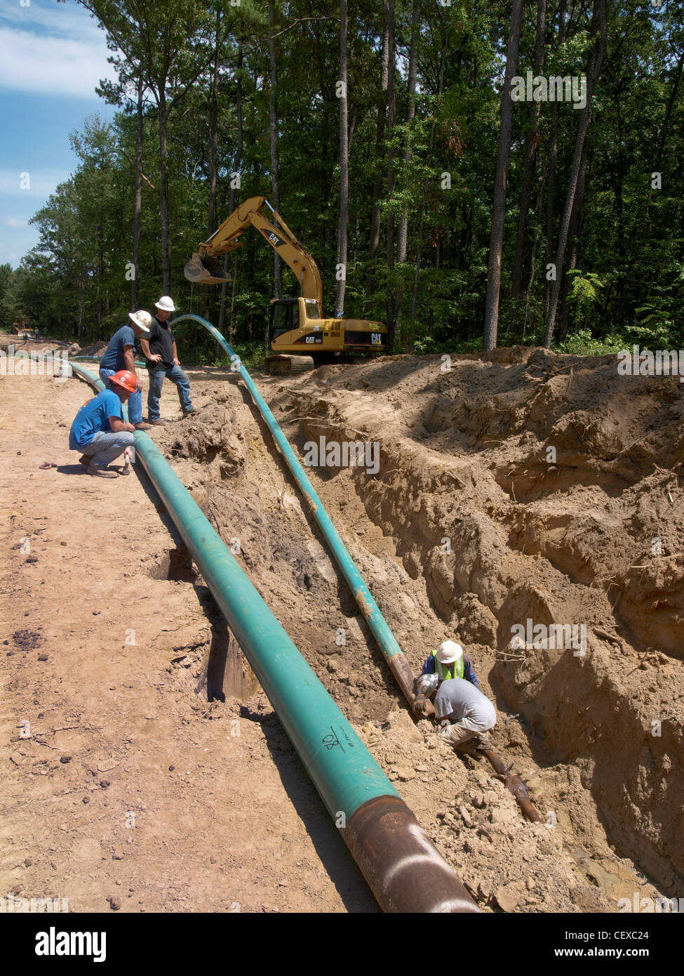 Workers check pipe before it gets pulled under railroad tracks in ...