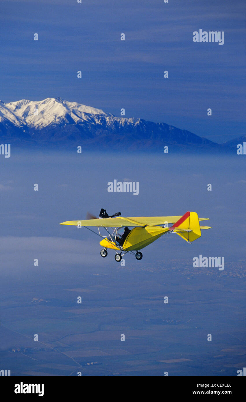 Ultra light plane flying in wintertime. At background Canigou peak ...