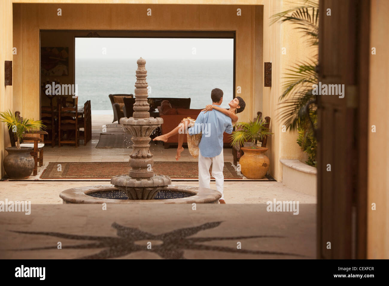 Hispanic man carrying wife across courtyard Stock Photo - Alamy